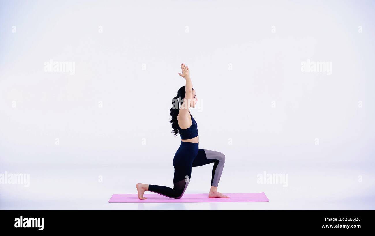 side view of barefoot woman exercising on yoga mat on white Stock Photo ...