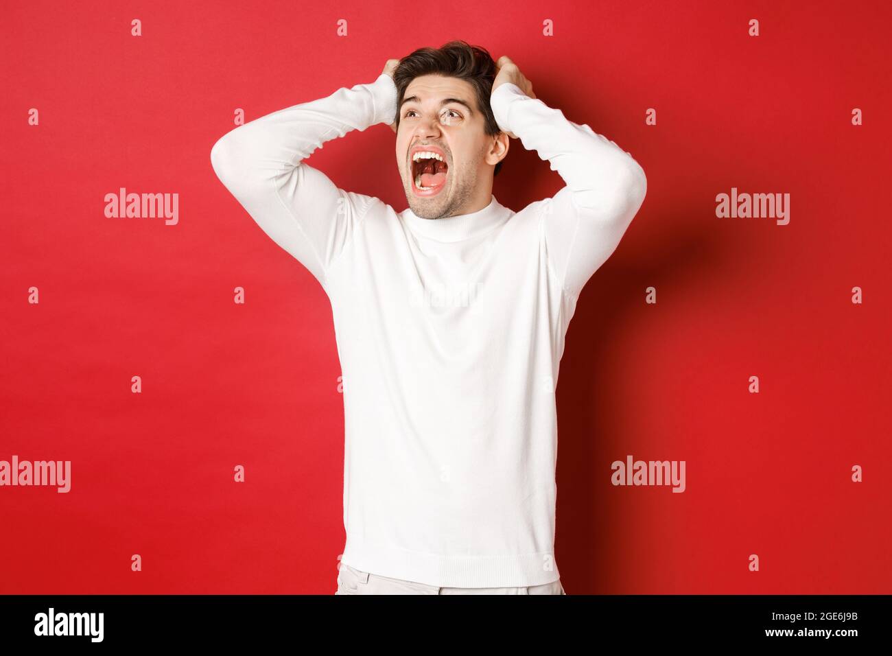 Portrait of frustrated man in white sweater, screaming in panic and ...