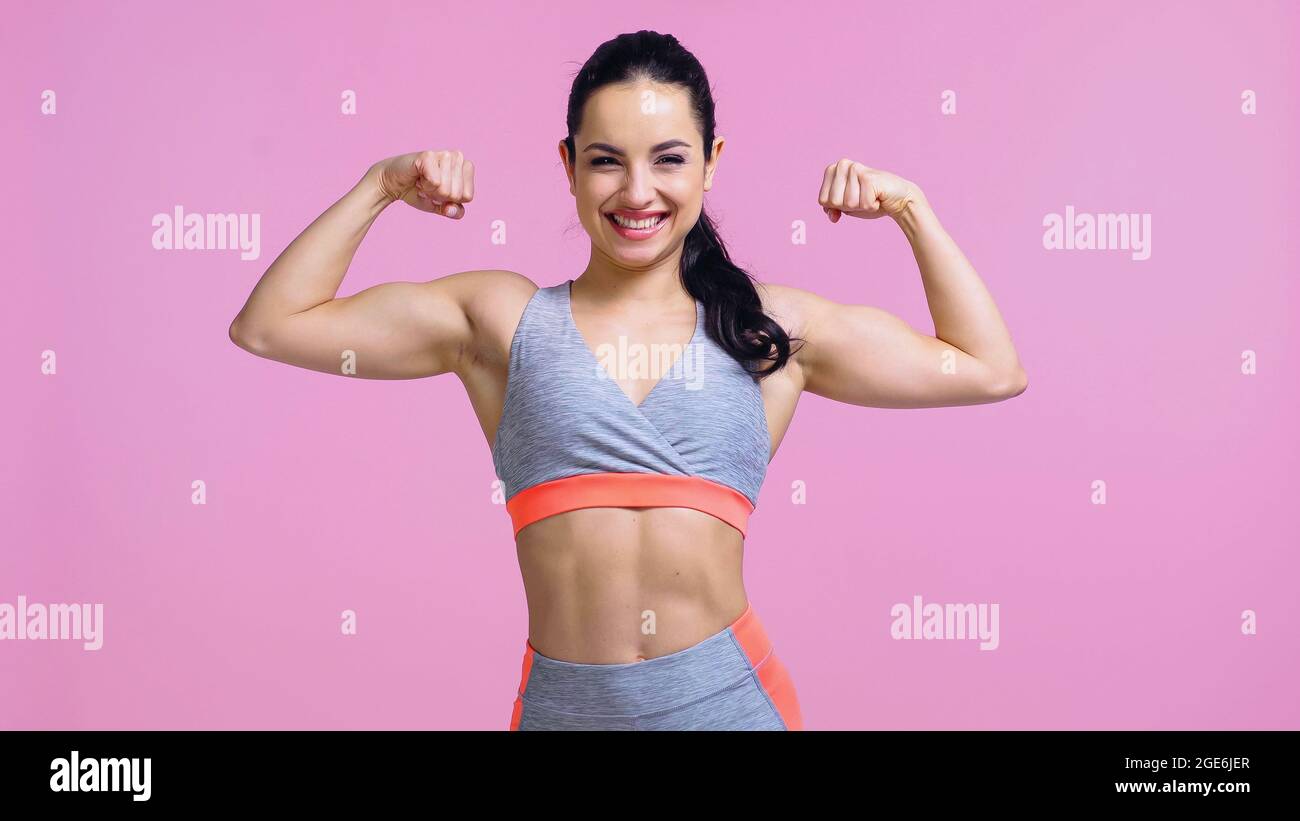 positive sportswoman showing muscles isolated on pink Stock Photo - Alamy