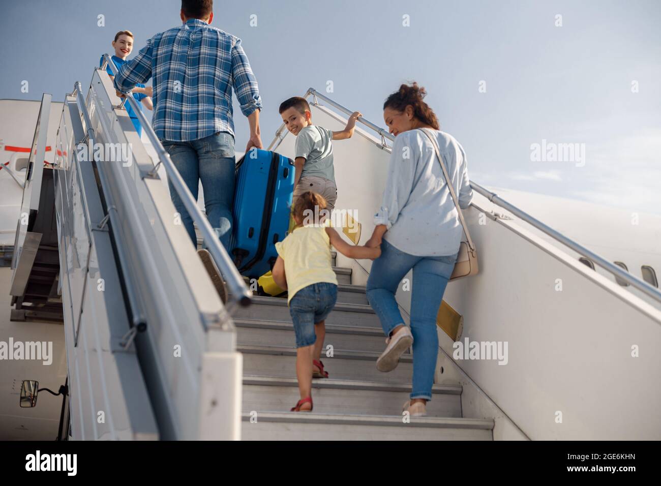 Back view of parents with two kids getting on, boarding the plane on a ...