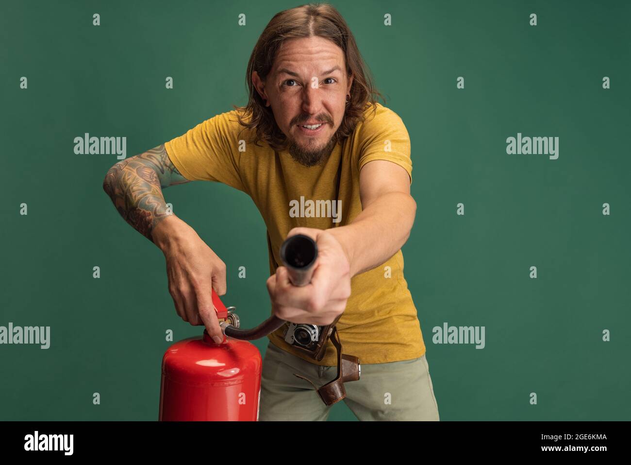 Comic portrait of young man with fire extinguisher having fun isolated ...