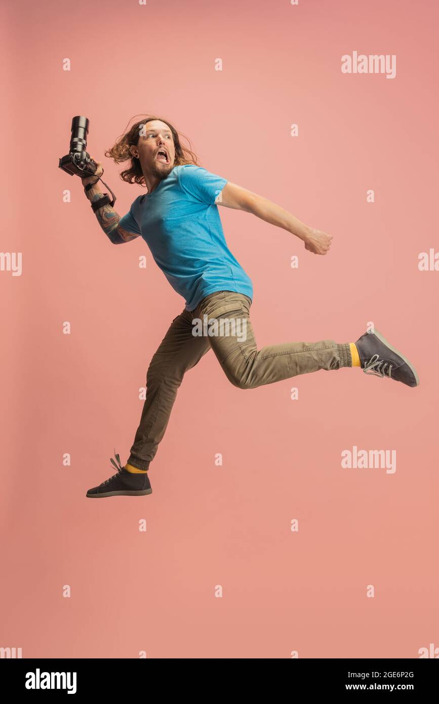 Portrait of young man, photographer, cameraman with camera jumping ...