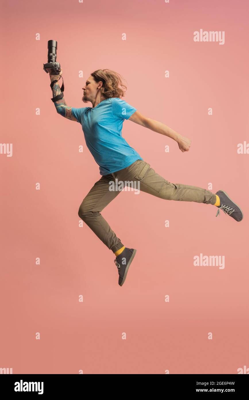 Portrait of young man, photographer, cameraman with camera jumping ...