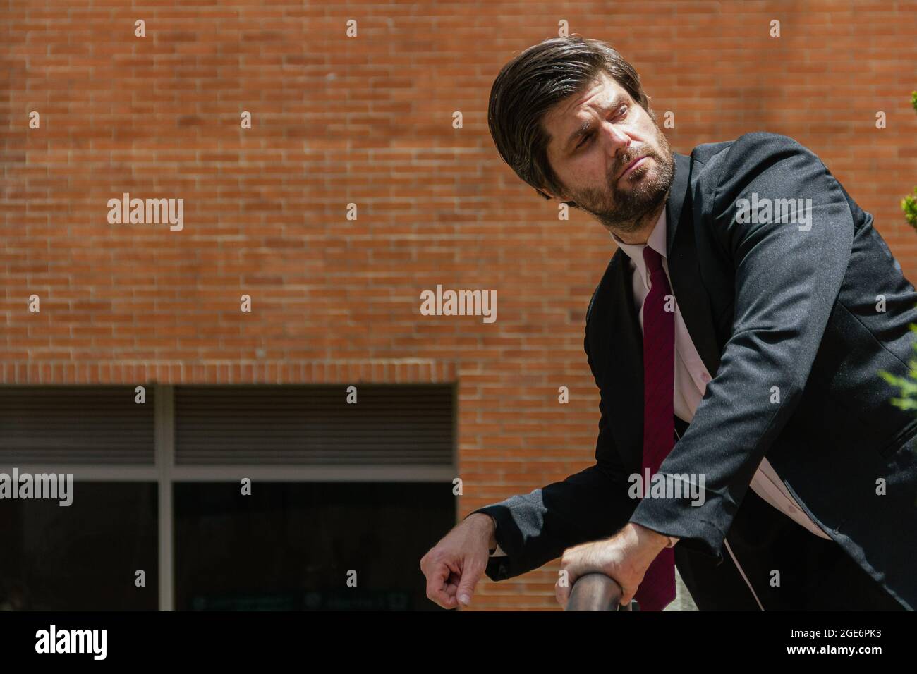 elegant man wearing a black suit and red necktie lean on railing Stock ...