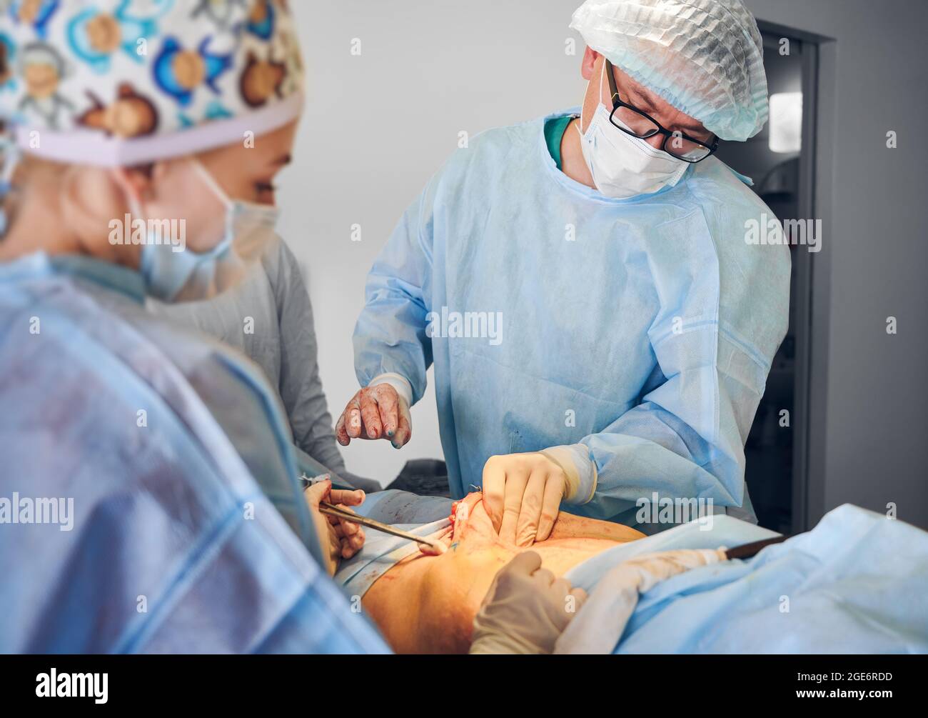 Plastic surgeon and assistant performing plastical surgical operation ...