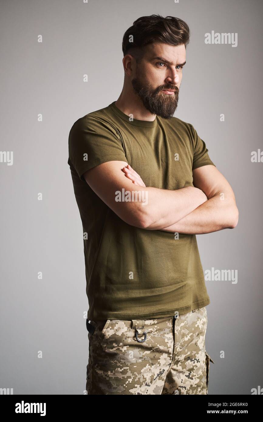Portrait of a handsome military man holding arms crossed on gray ...