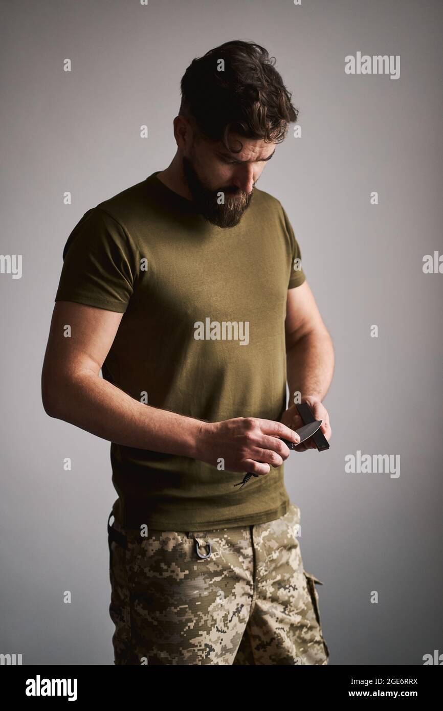 Strong military man sharpening his pocket knife with a whetstone Stock ...