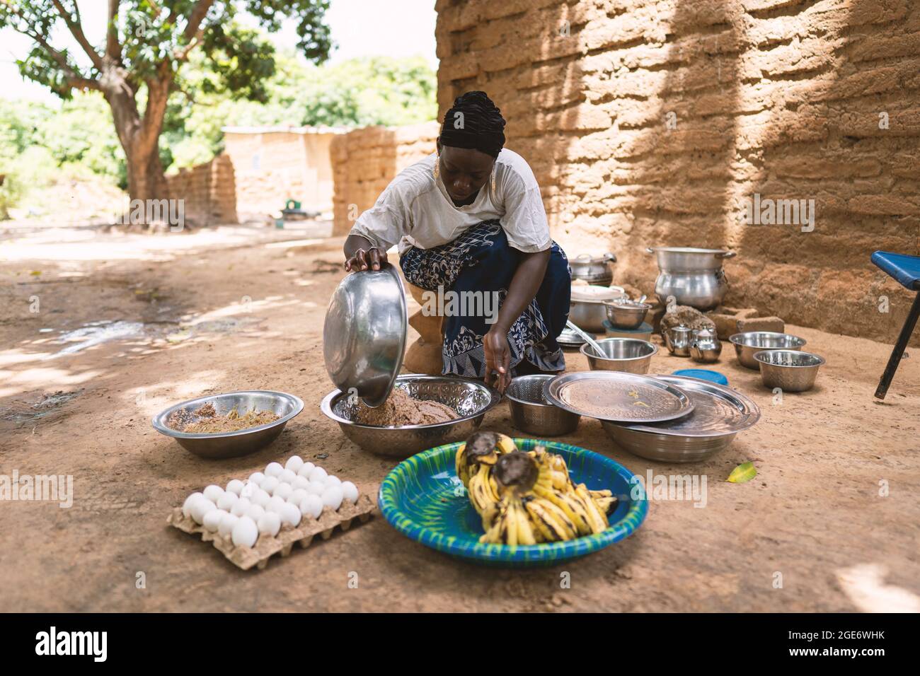 Black African housewife sitting in the middle of her cooking utensils ...