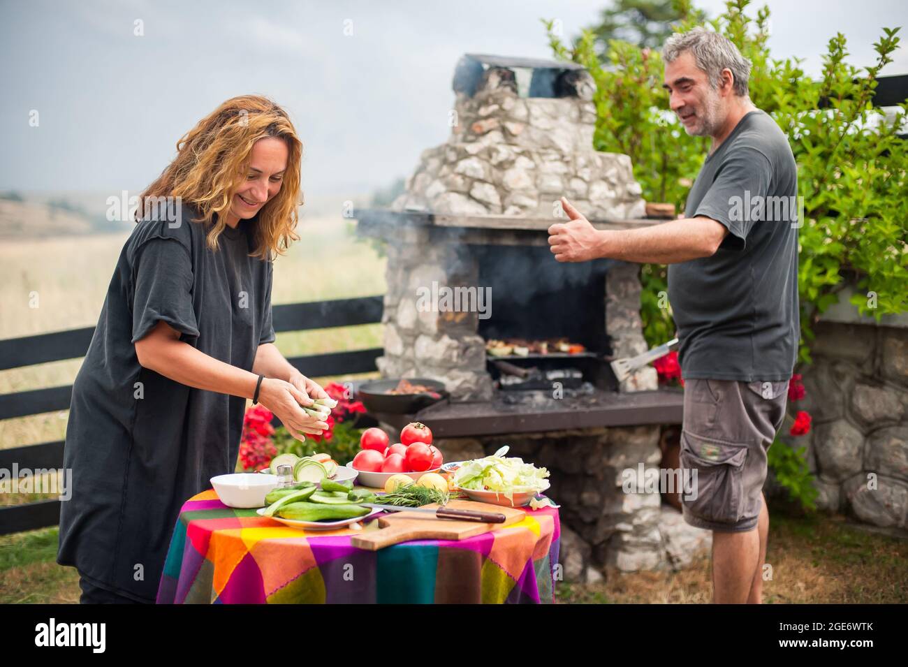 BBQ grilling party. Couple in garden making barbecue grill. Food ...