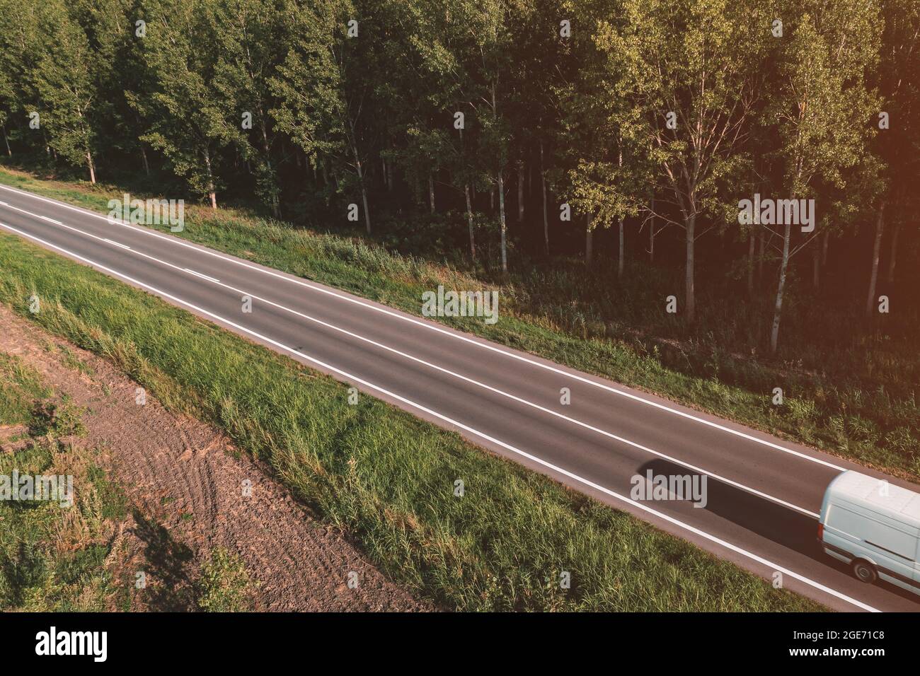 Aerial view of mini van on the road through green forest landscape in ...
