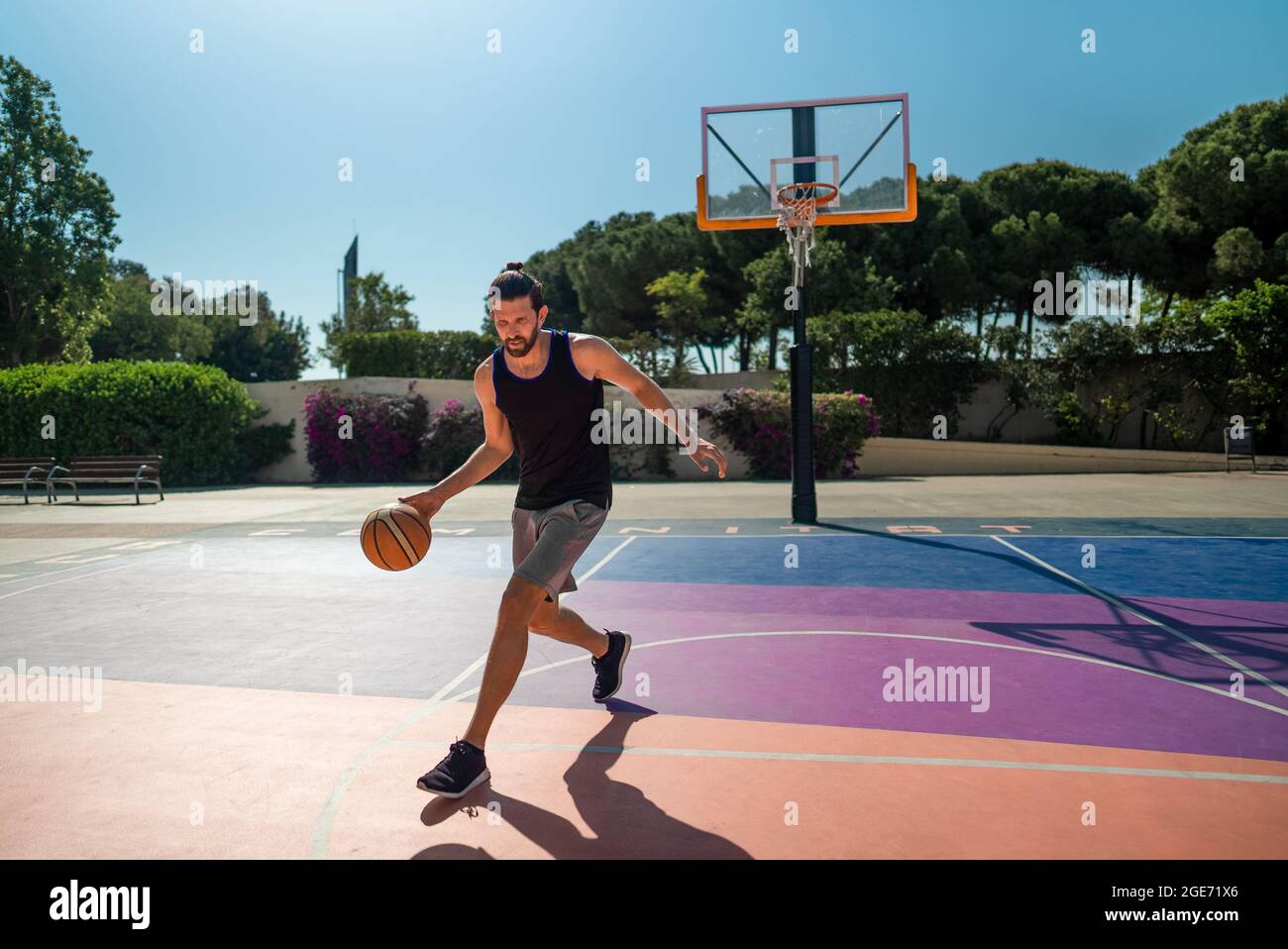 A male basketball player trains himself on a basketball court with a ...
