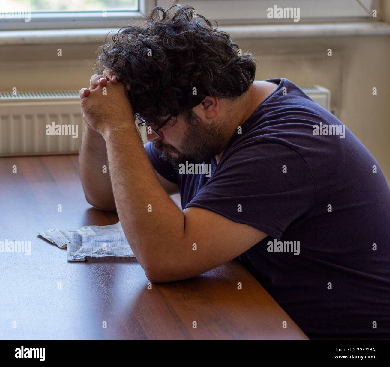 Man with various bills in front of him. A man who cannot pay his debts ...