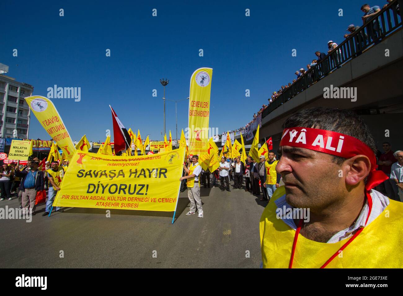 A man wearing a headband praising Imam Ali marches in front of a banner ...