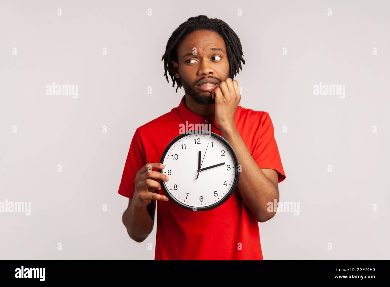 Nervous man with dreadlocks wearing red casual style T-shirt, biting ...