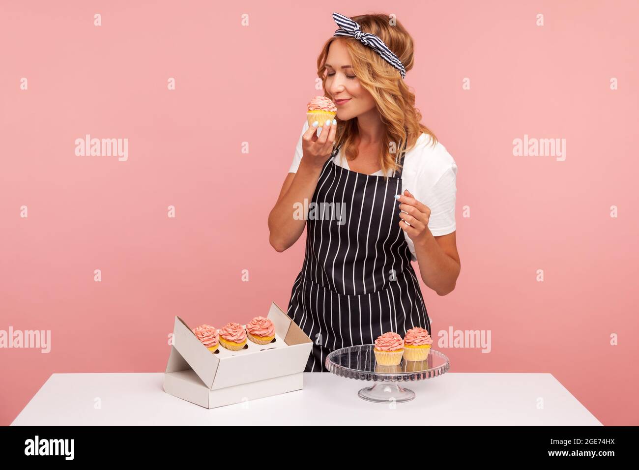 Blonde young adult baker takes out cakes from paper box, preparing for ...