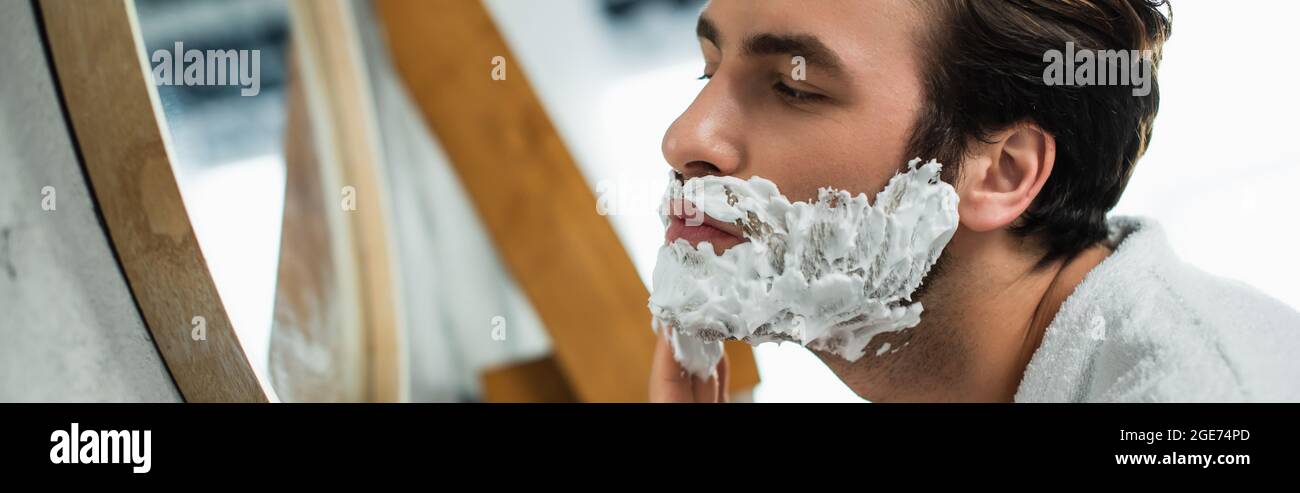 man applying shaving cream on face near mirror, banner Stock Photo - Alamy