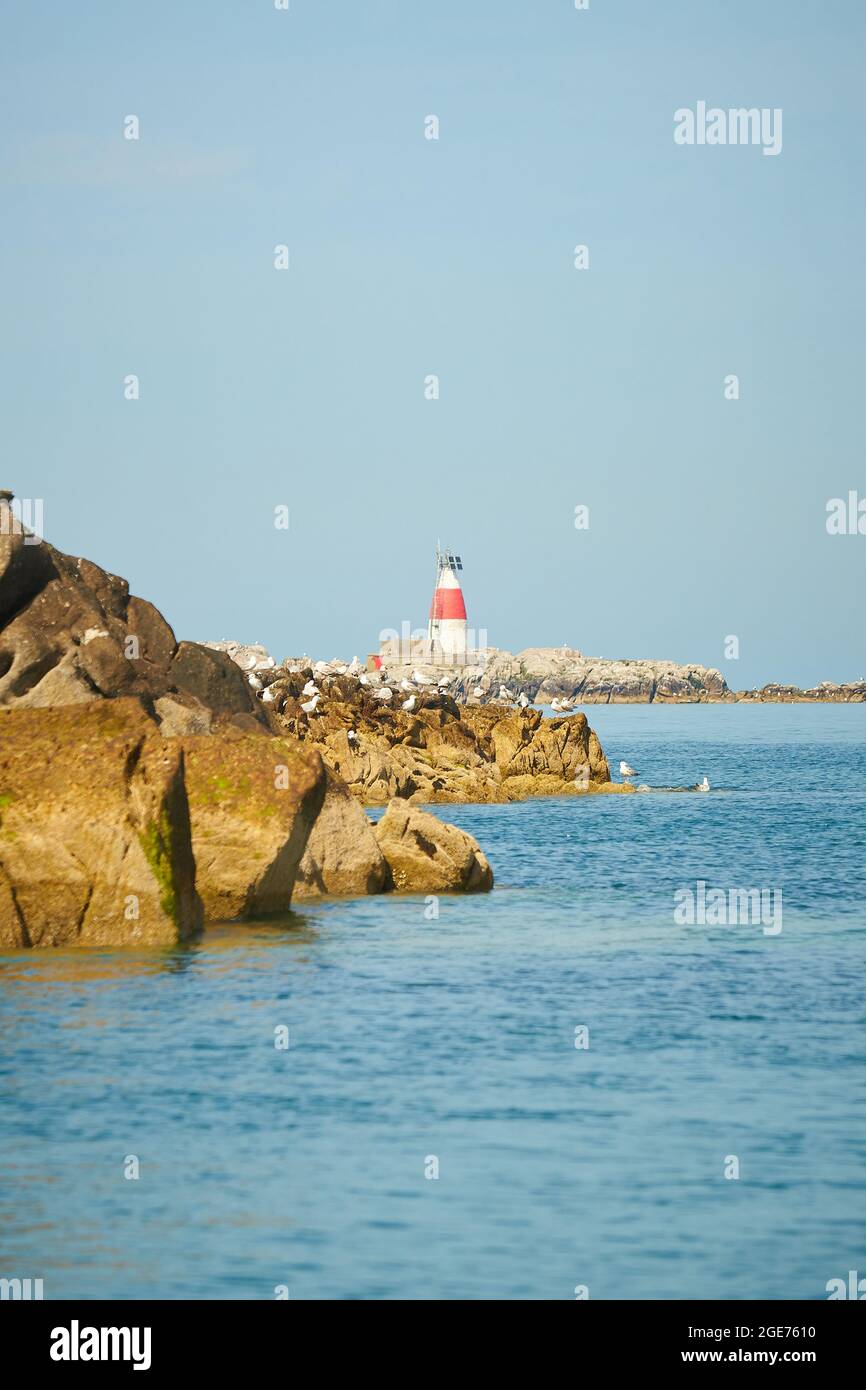 Old Muglins Lighthouse on the isolated island the backdrop of the blue ...