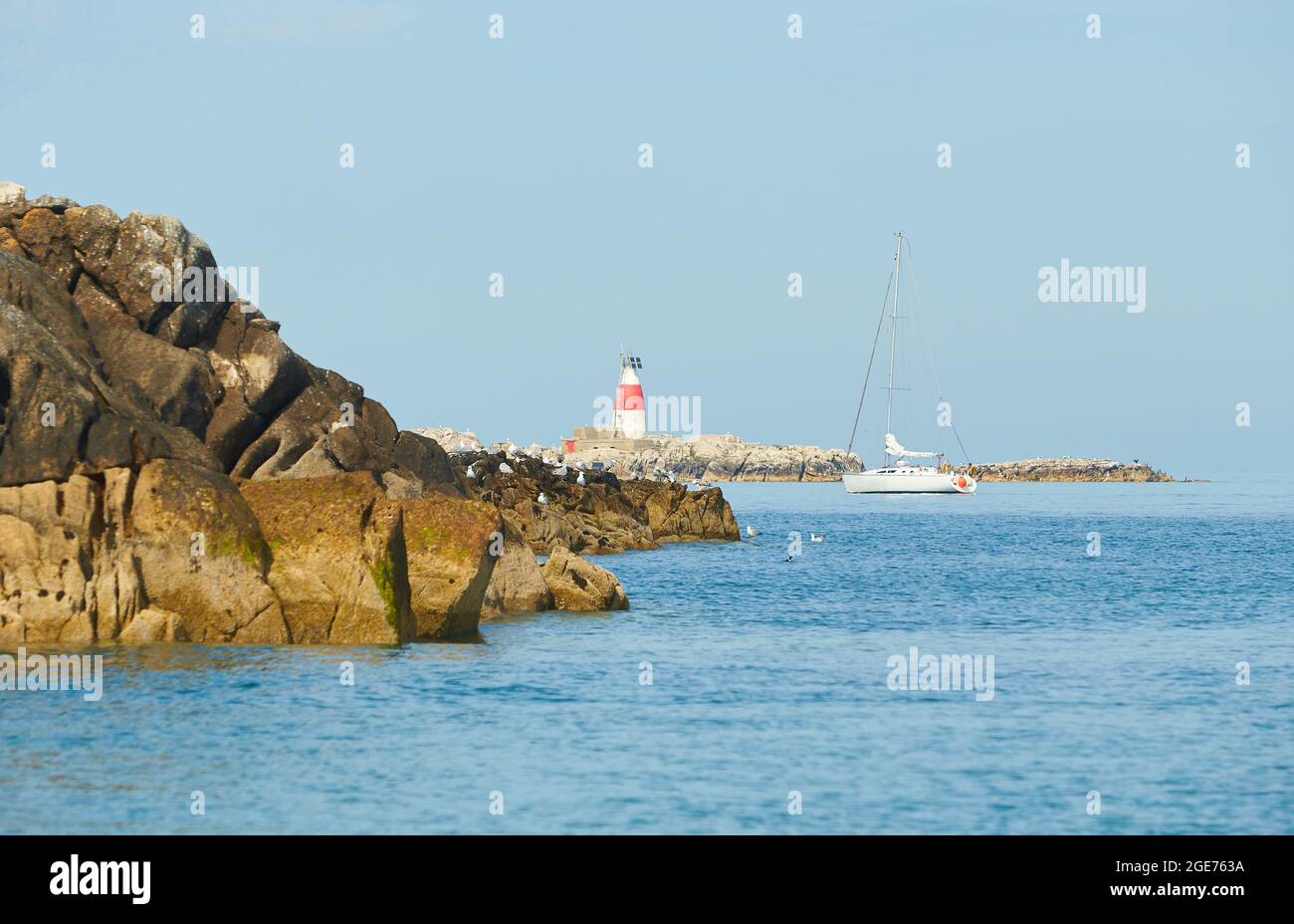 Old Muglins Lighthouse on the isolated island the backdrop of the blue ...
