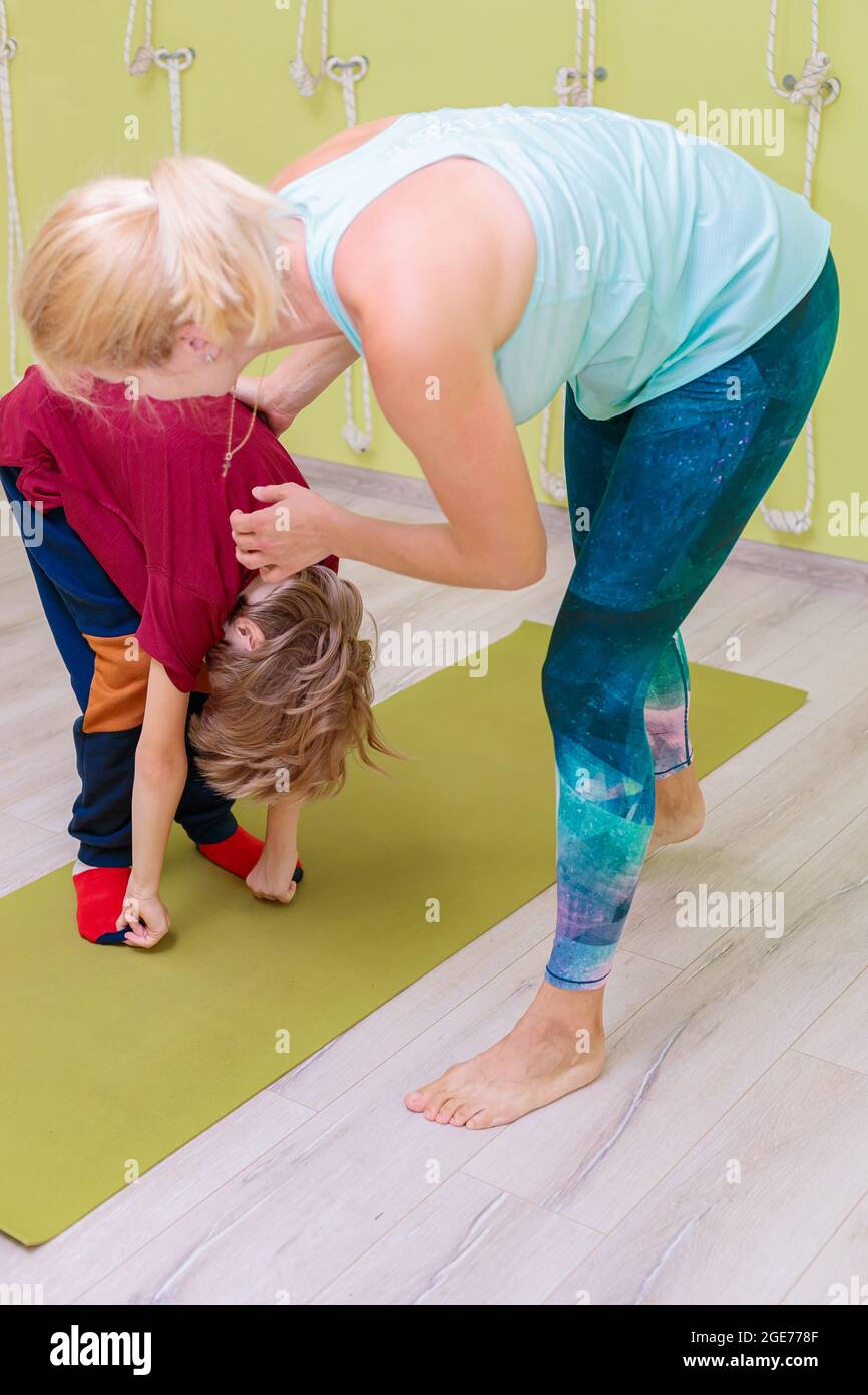 A woman instructor in a sports uniform is engaged in yoga with a boy ...