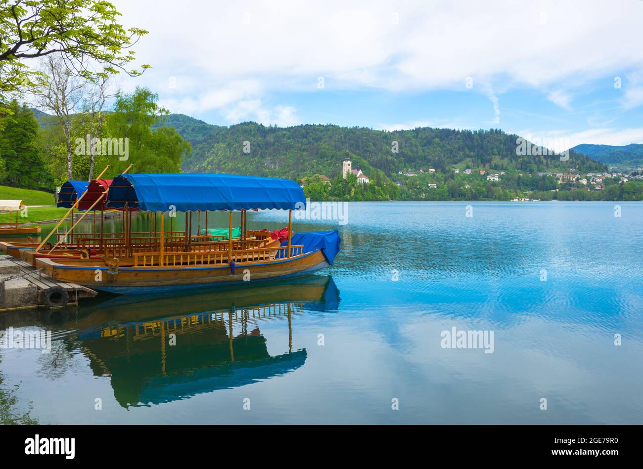 Traditional Pletna boat waiting for tourists on Lake Bled, with the ...