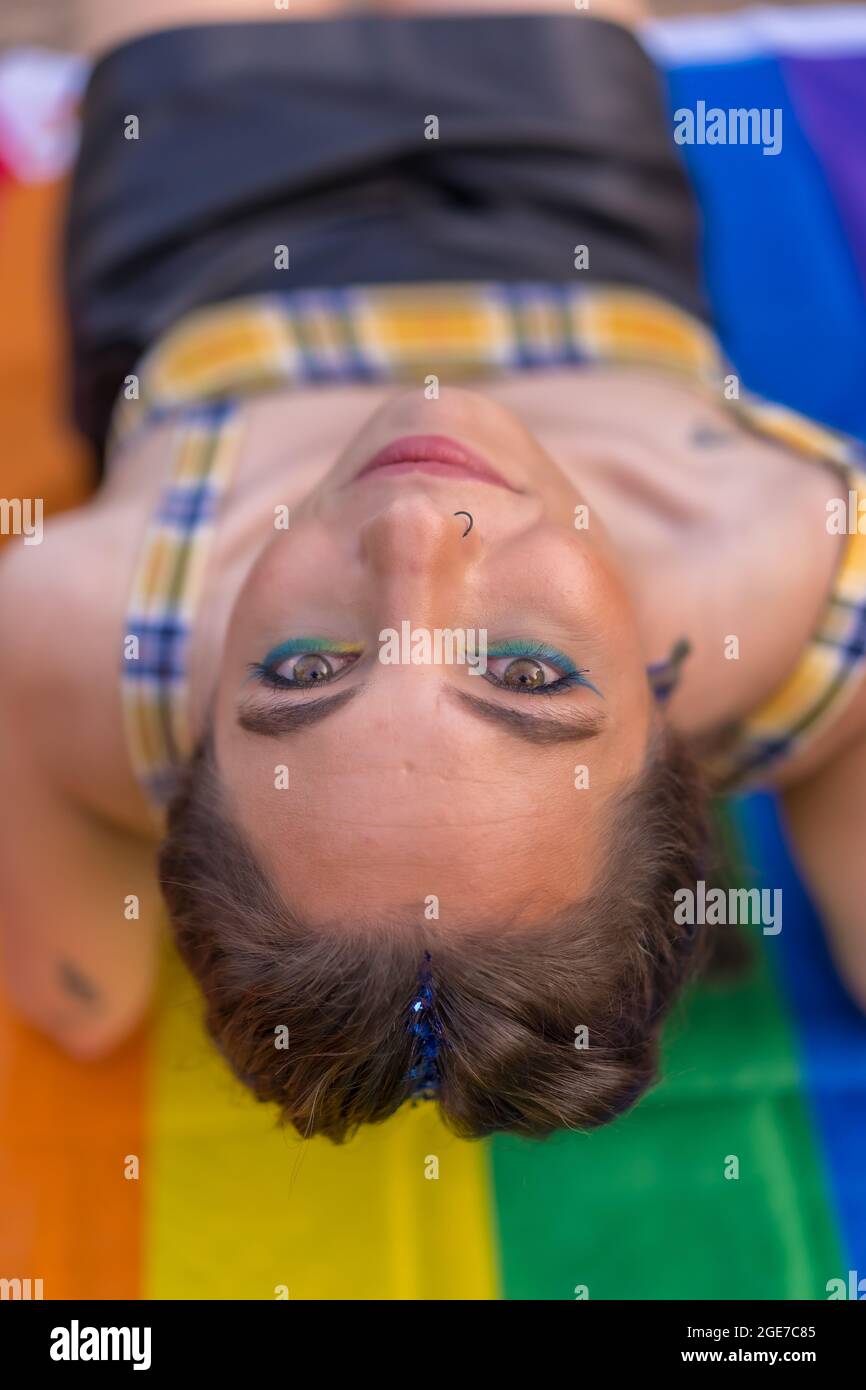 Vertical closeup shot of a young female posing laying on a rainbow ...