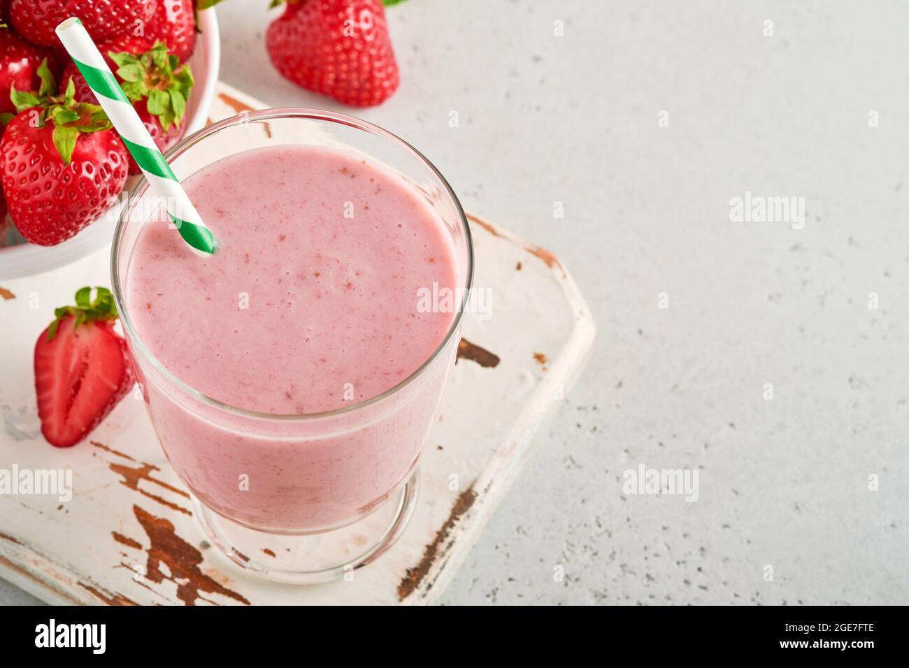 Strawberry smoothie or milkshake with berries and mint in tall glass on ...