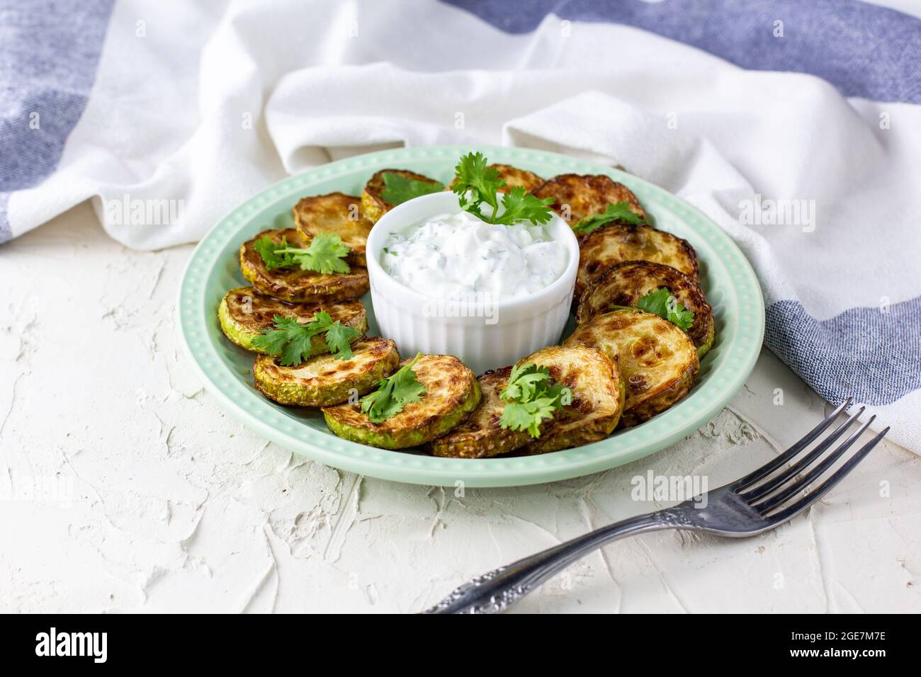 Fried slices of zucchini with sour cream sauce on plate. Fried ...