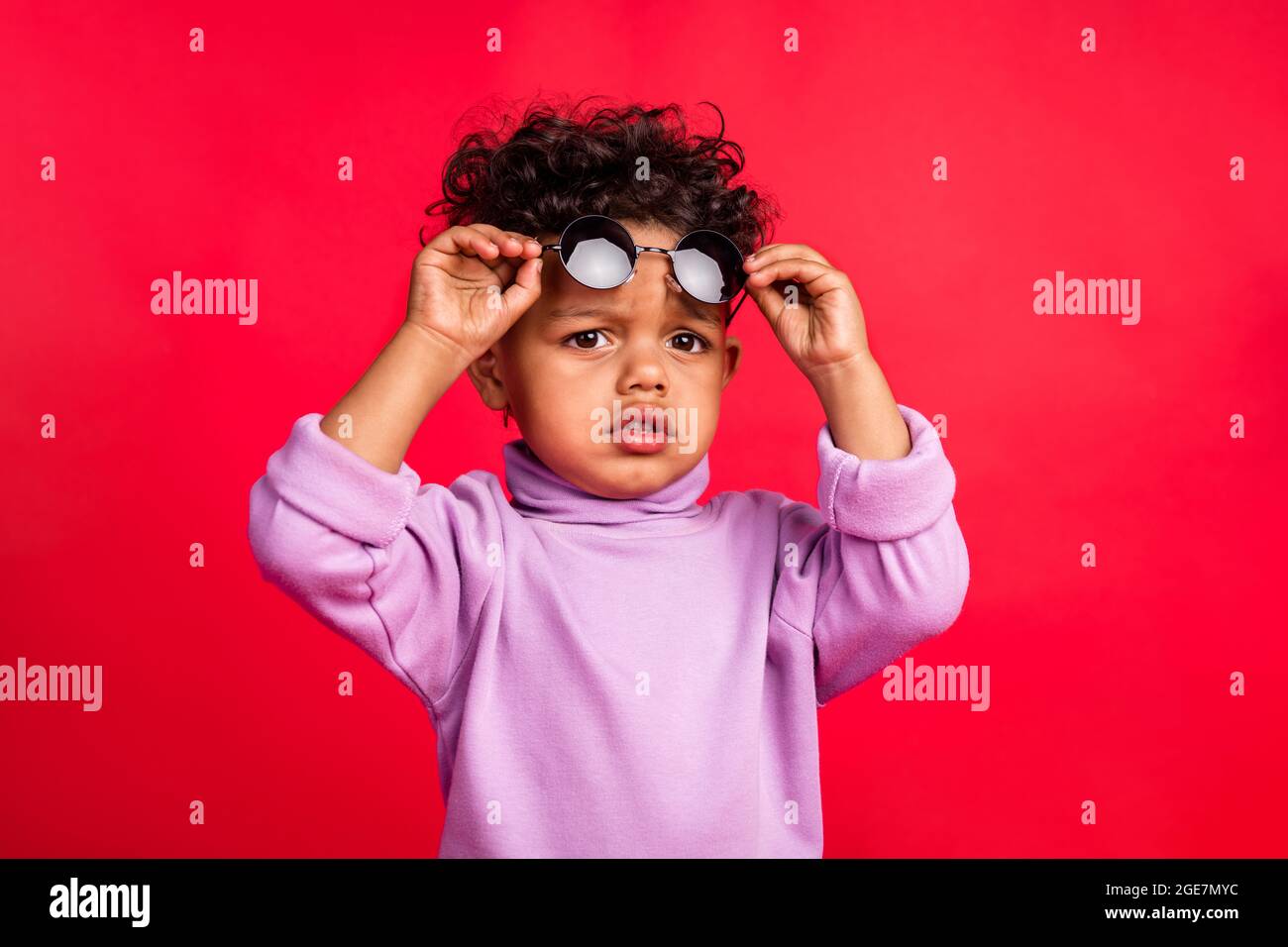 Portrait of attractive suspicious doubtful kid touching specs looking ...