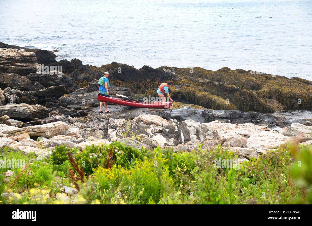 A couple prepares to launch a kayak off the rocky coast of East ...