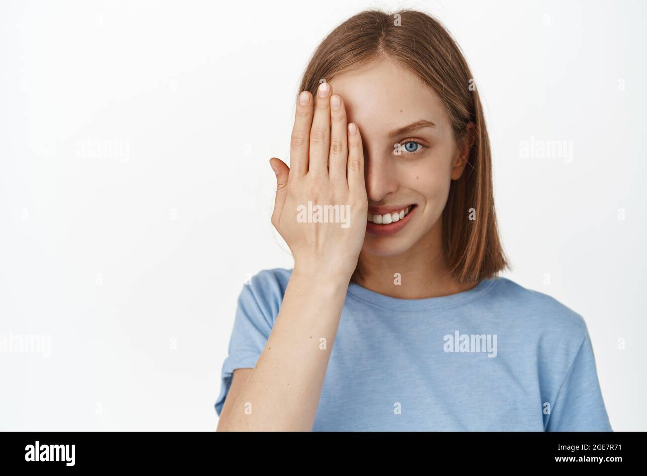 Portrait of cute young woman with short blond hair, cover half of face ...