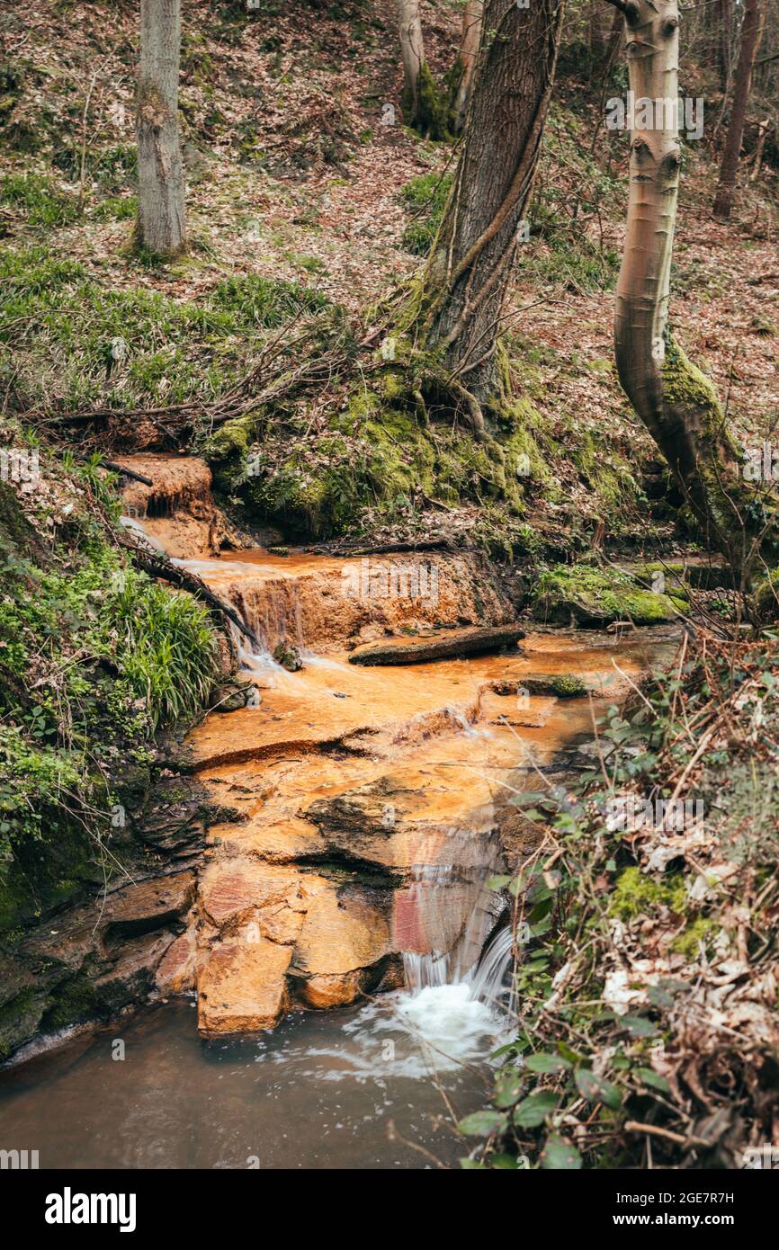 small waterfall running over orange rock shelf in the woods Stock Photo ...
