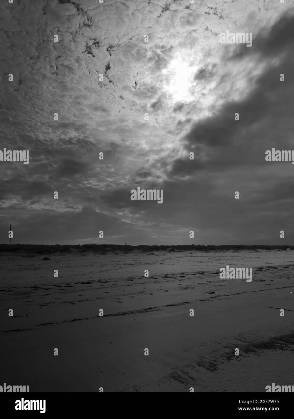 Bleak, dramatic view across a sea coal spotted beach to a horizon of ...