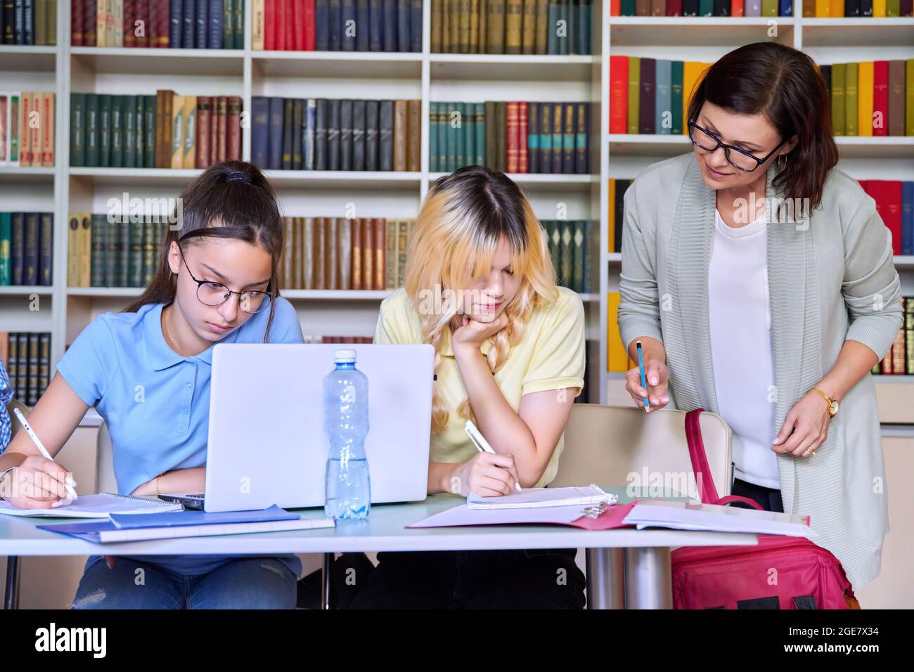 Girls teenage students studying in library with teacher mentor Stock ...