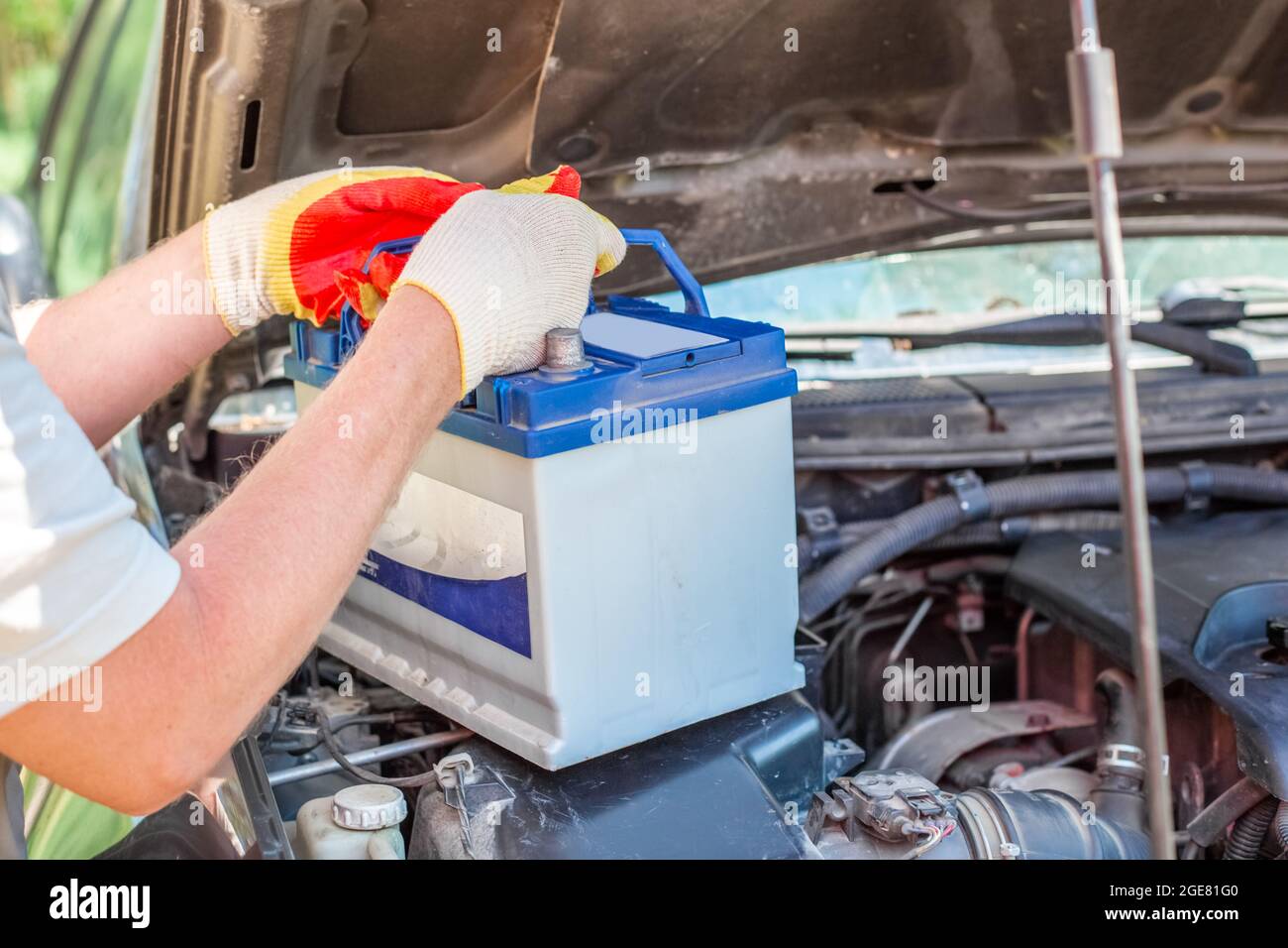 Maintenance of the machine. A male car mechanic takes out a battery ...