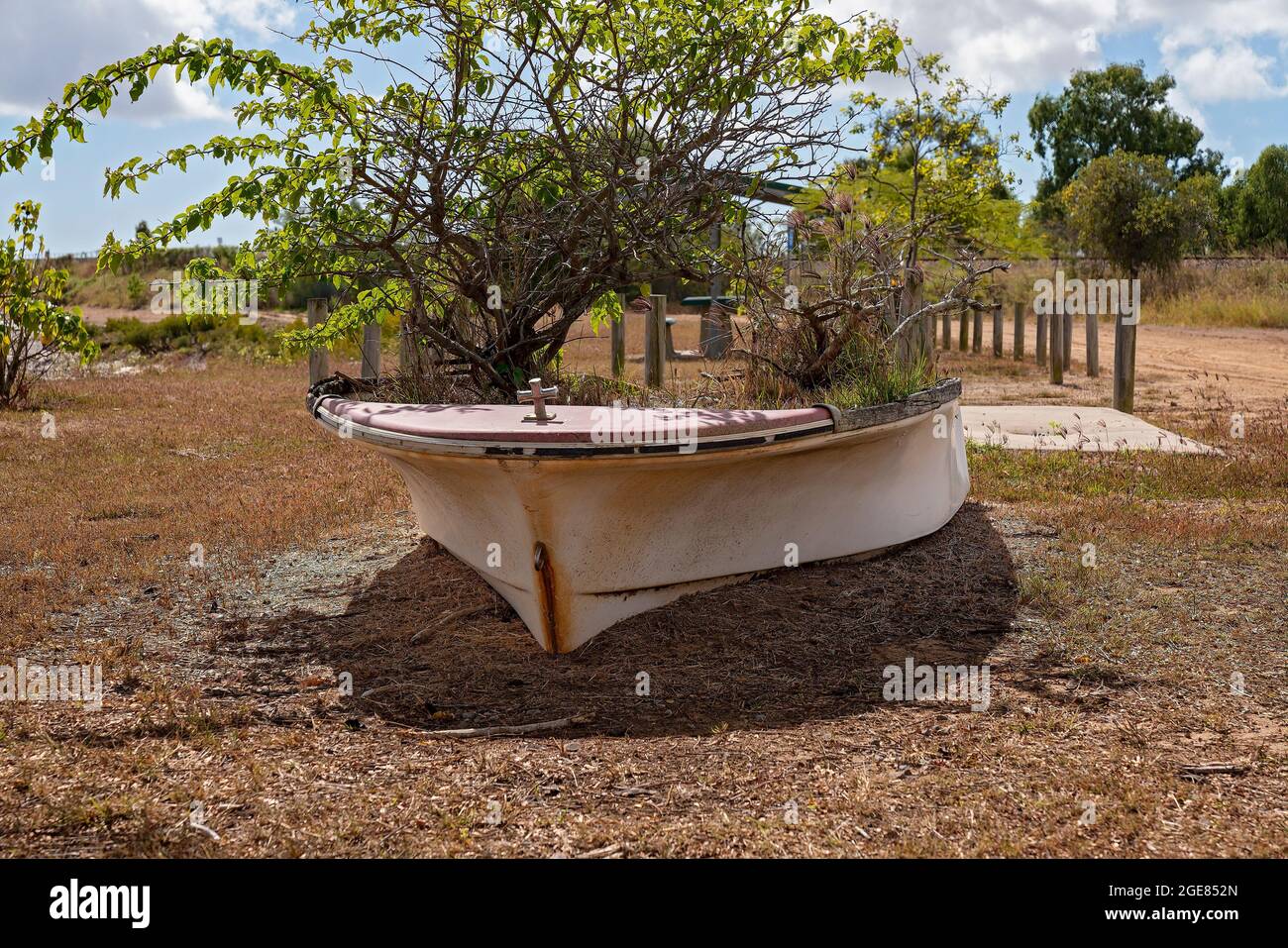 A small boat filled with dirt and growing trees in a dry tourist park ...