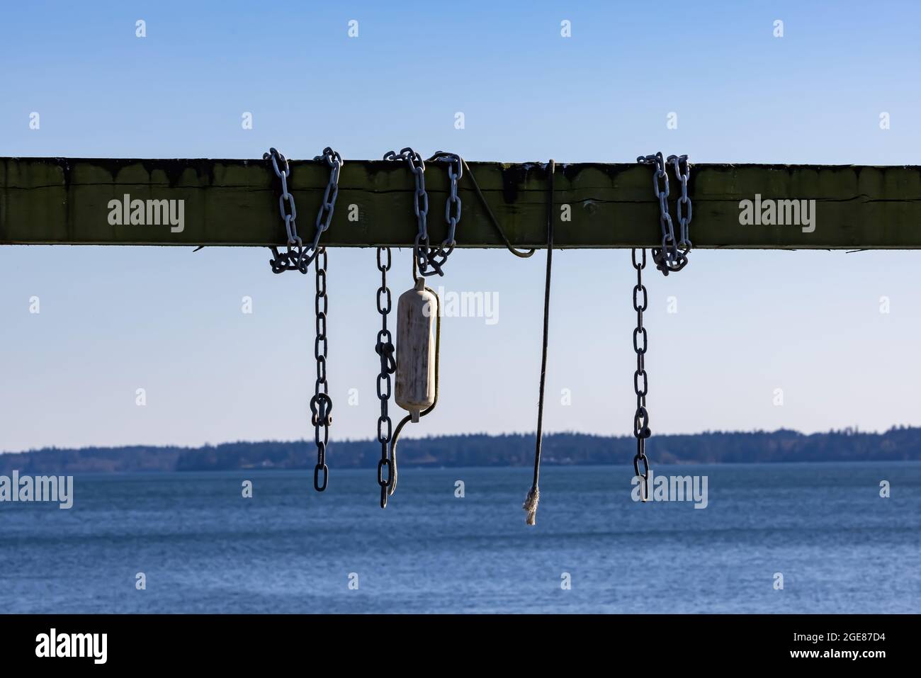 ropes chains and bouys hanging on a wooden beam out on a boat launch ...