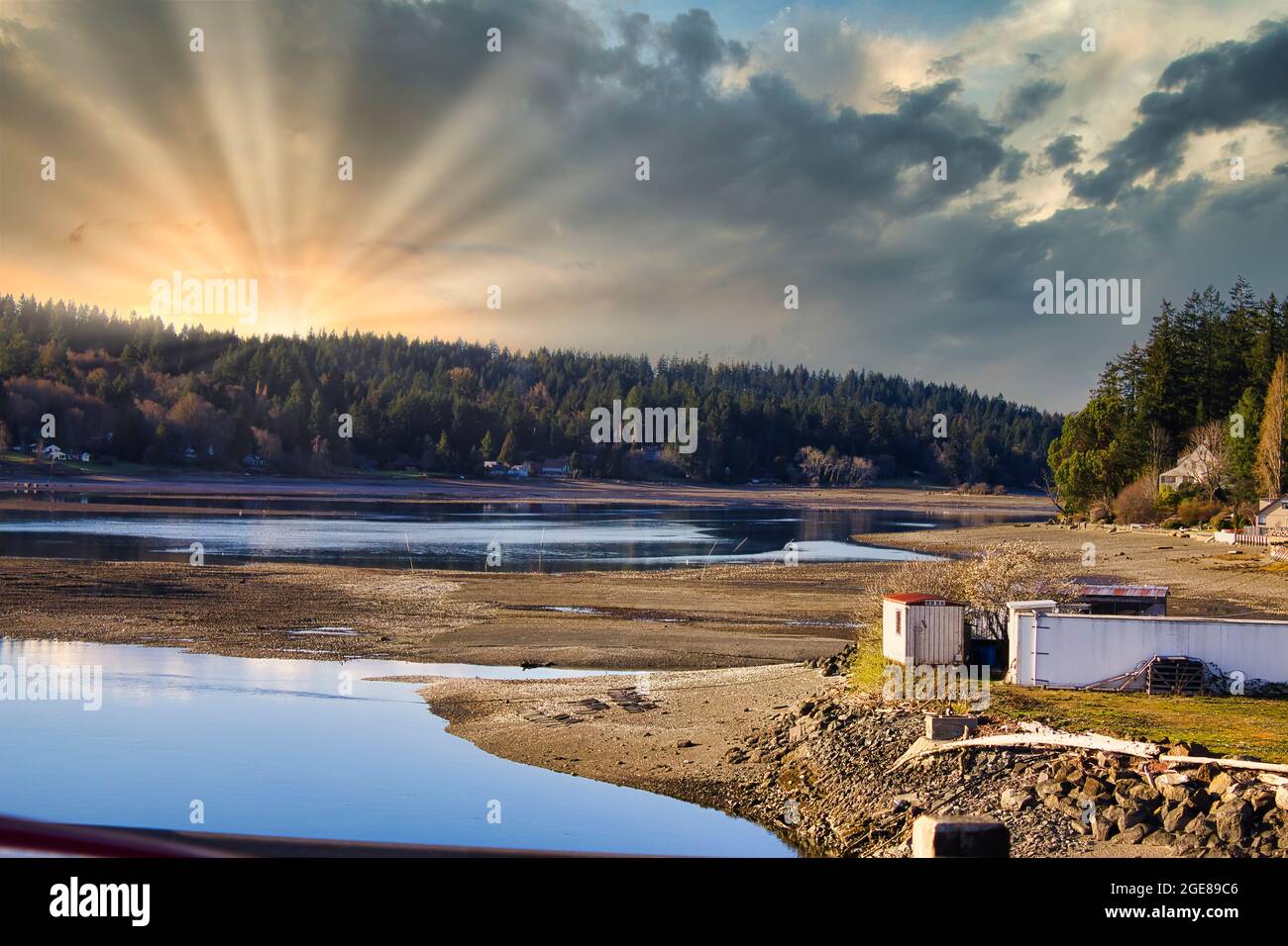 Golden bright sun beams from sunset over hills above the sea Stock ...