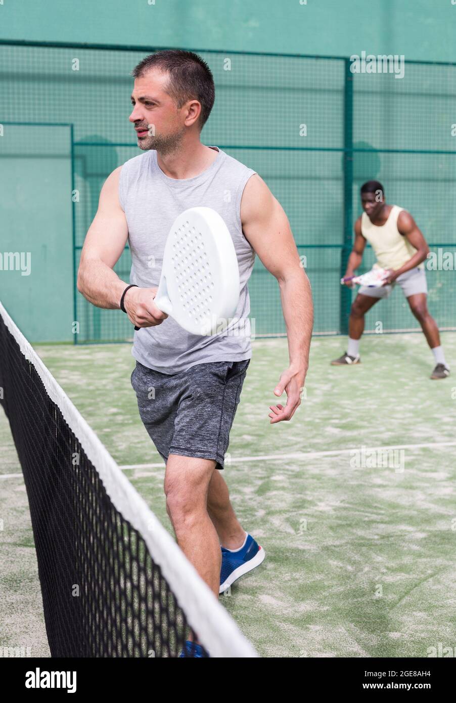 Athletic mens plays padel. View through tennis net Stock Photo - Alamy