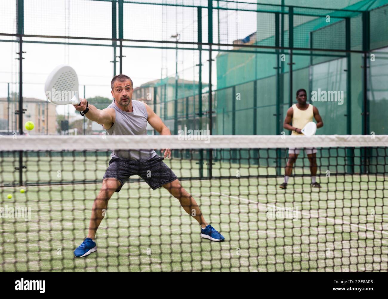 Athletic mens plays padel. View through tennis net Stock Photo - Alamy