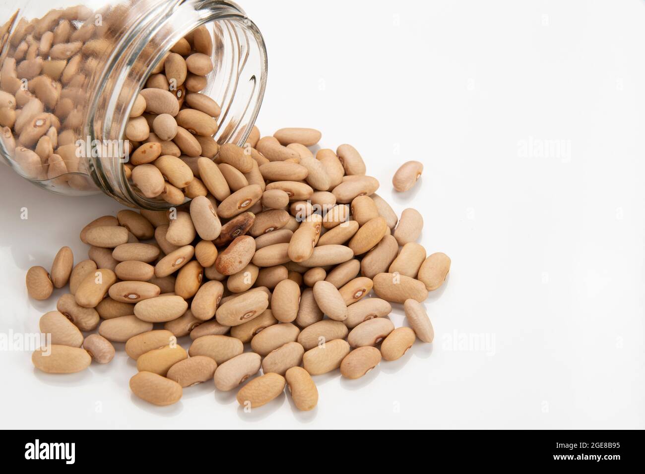 glass pot with beans pouring out in a white background Stock Photo - Alamy