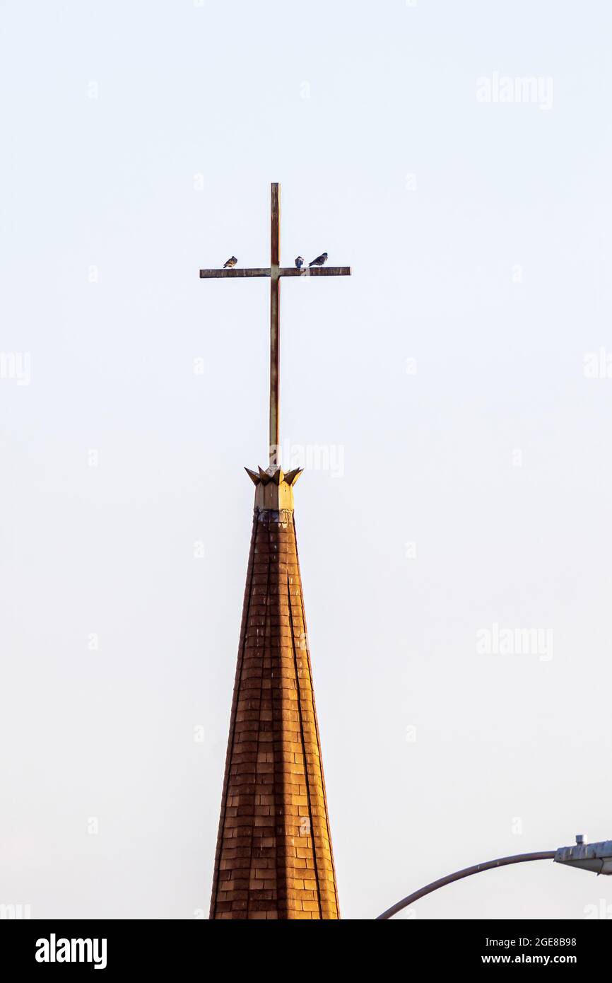 a cross on top of a tall steepled roof of a city church Stock Photo - Alamy