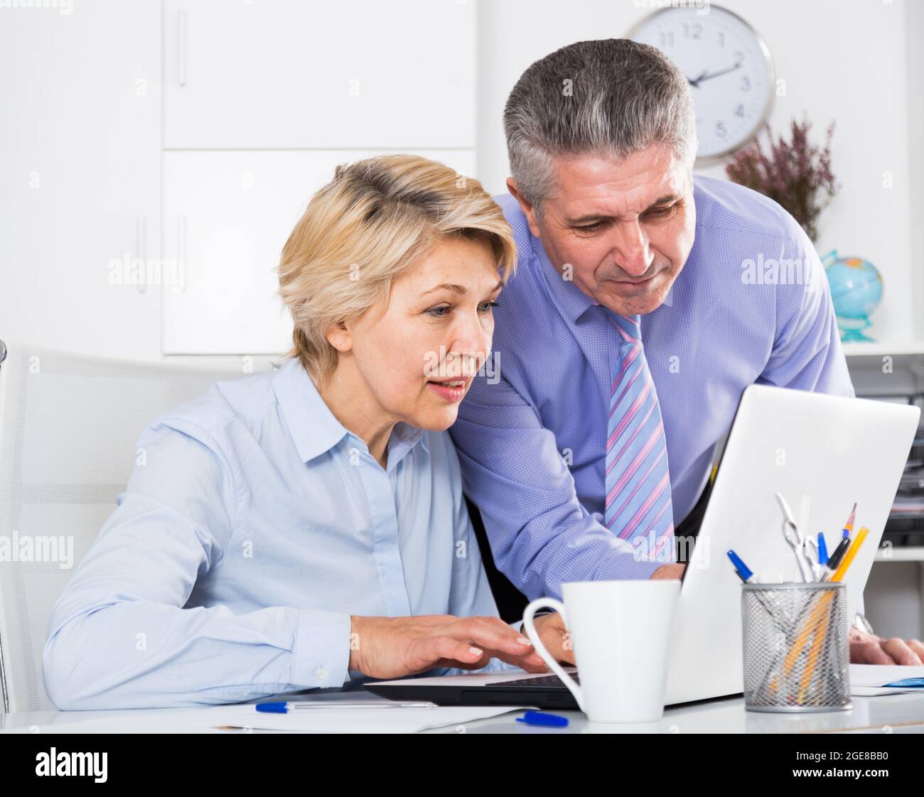 Mature man helping his colleague Stock Photo - Alamy