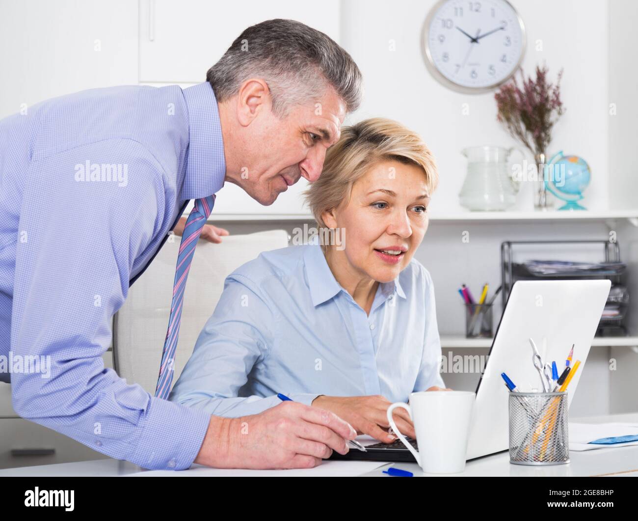 Mature man helping his colleague Stock Photo - Alamy