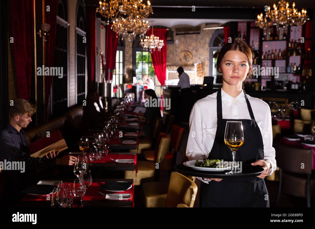 Female waiter standing with serving tray, recommending dishes in ...