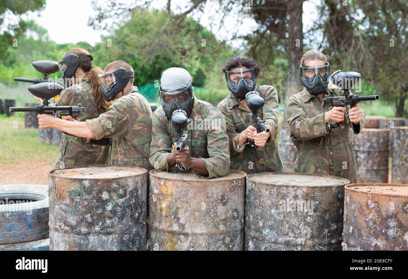 Group of people in full gear playing paintball on shooting range ...