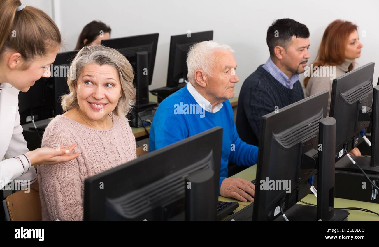 Mature people studying with young female coach Stock Photo - Alamy