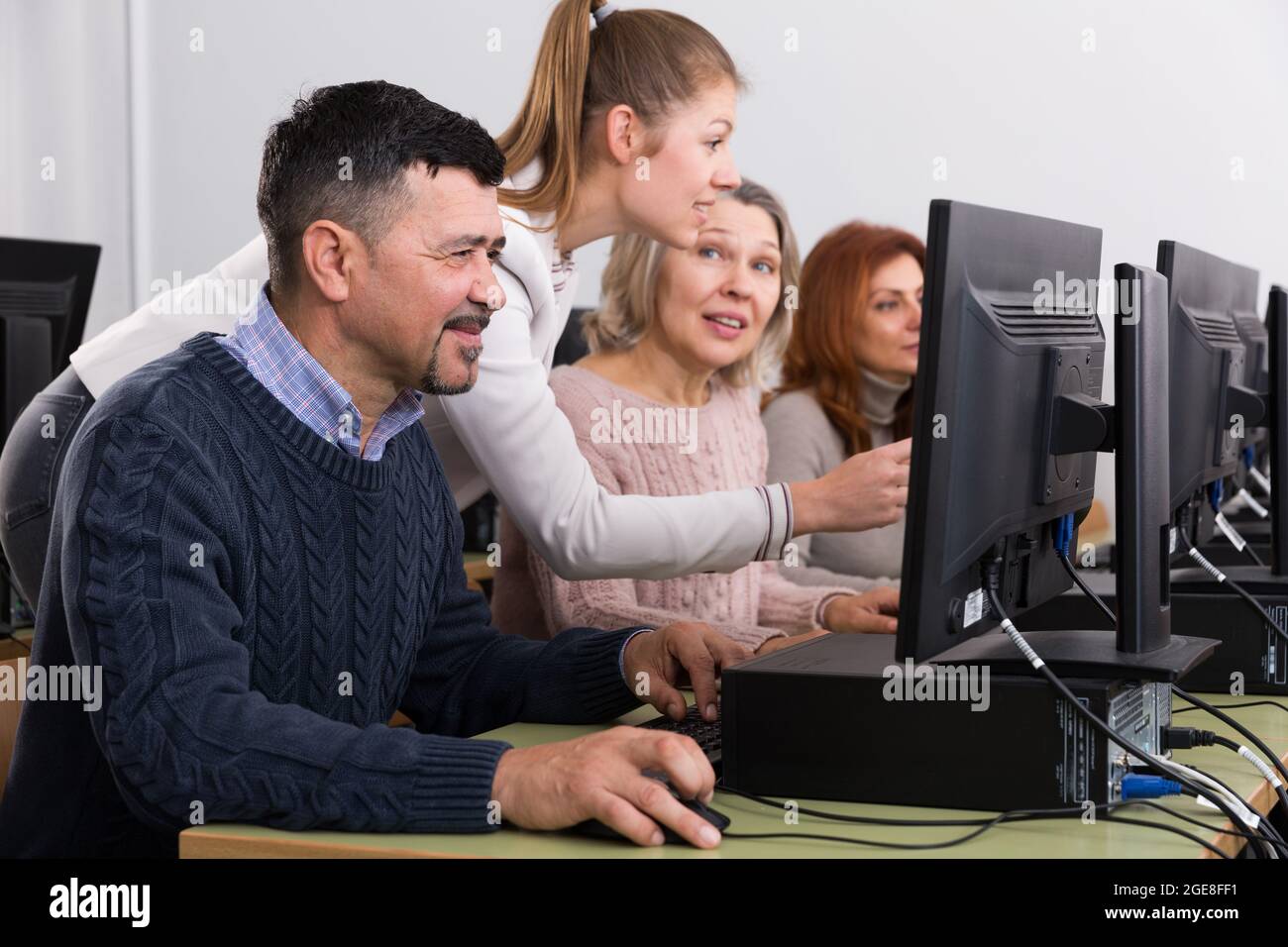 Young female coach giving computer lessons Stock Photo - Alamy