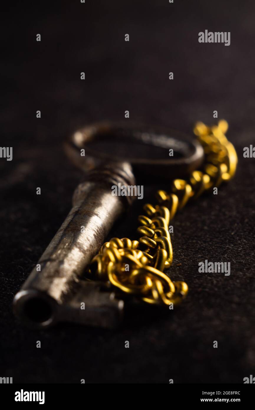 Old key with a golden chain on a textured surface Stock Photo - Alamy