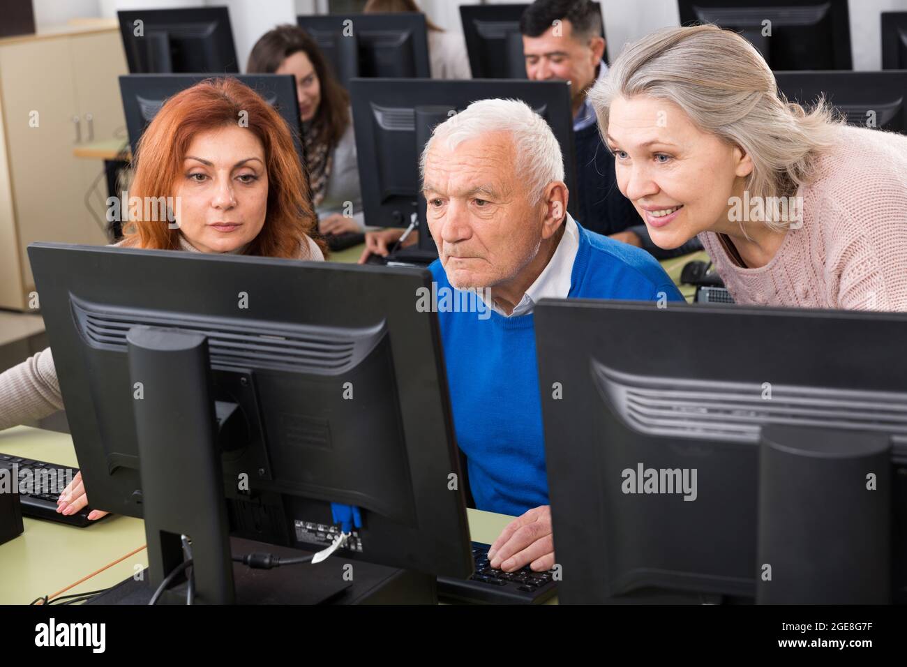 Three coworkers working around computer monitor, talking about new ...