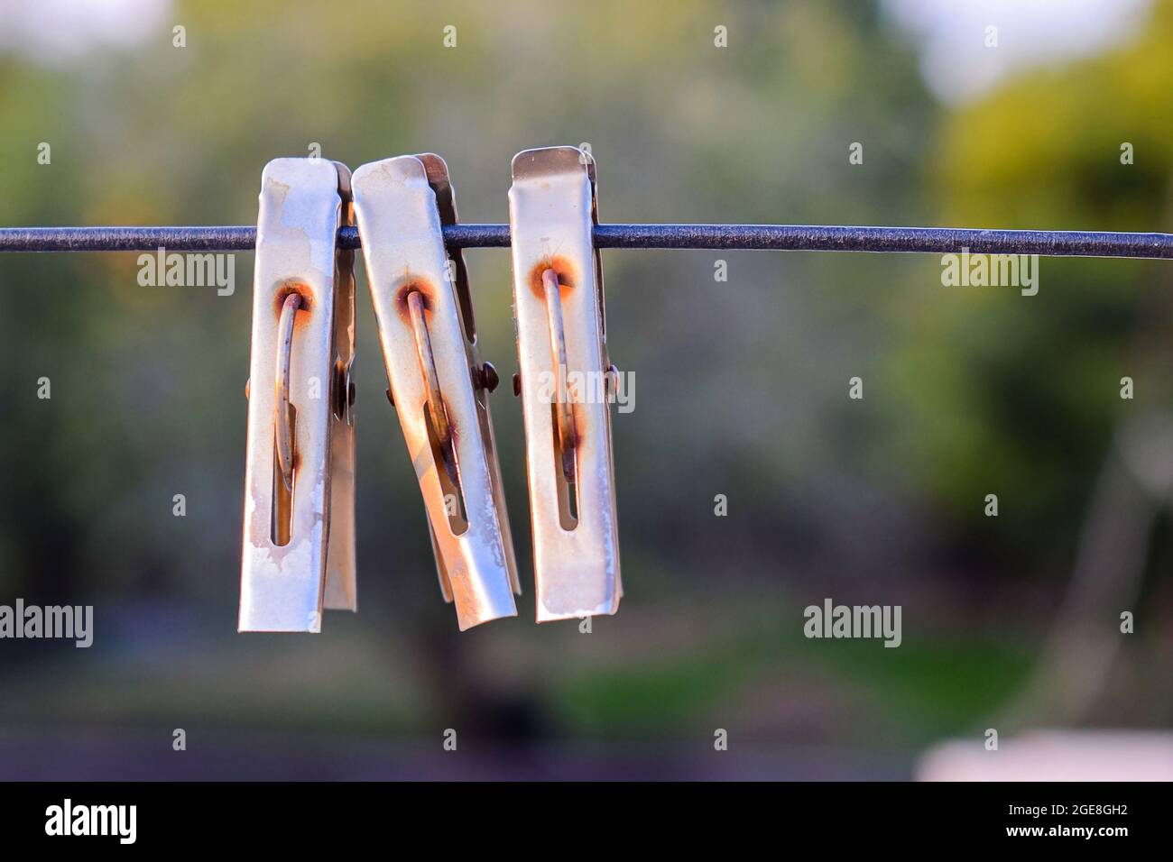 Rusty three metal clothespin hanging on a wire against a blurred ...